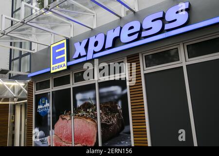 A logo sign outside of an Edeka Express retail grocery store in Munich ...