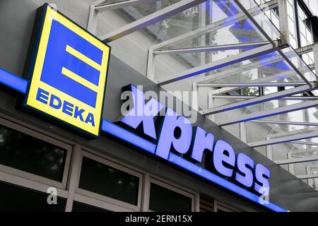 A logo sign outside of an Edeka Express retail grocery store in Munich ...