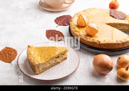 Autumn onion pie decorated with leaves and cup of coffee on gray ...