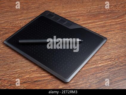 Ggraphic tablet drawing pad with digital pen stylus lies on table top ...