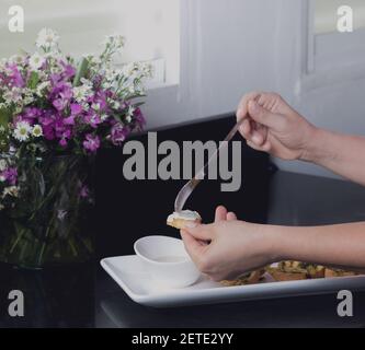 A closeup of hands spreading white sauce on bread Stock Photo - Alamy