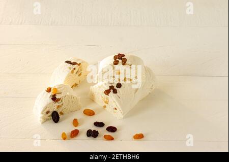 Sliced halva with nuts and dried fruits on a plate served with flowers ...