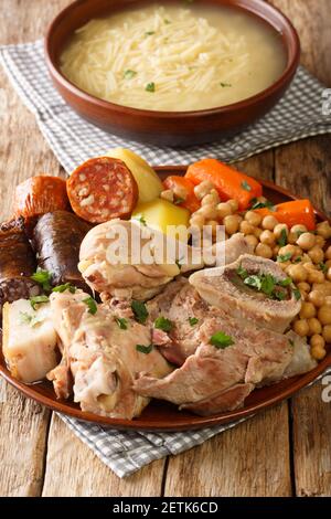 Madrid stew on a plate on a wooden table With bread and a glass of red ...
