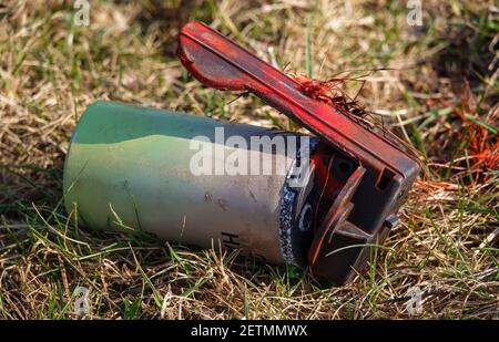 a discharged British Army red smoke grenade lying on mud and grass ...