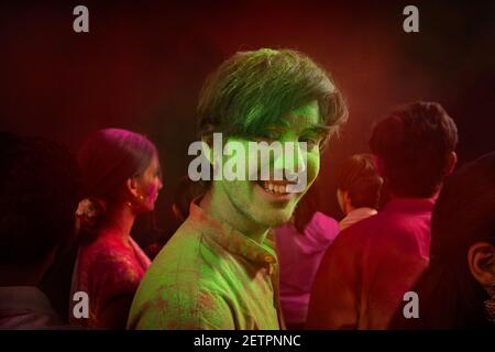 A YOUNG MAN WITH GULAL ALL OVER HIS FACE TURNING AROUND AND SERIOUSLY ...