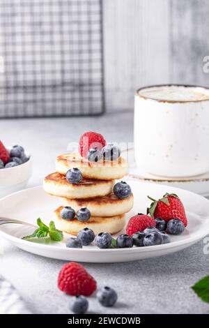 Stack of cheese pancakes with fresh berries, cup of coffee on the table ...