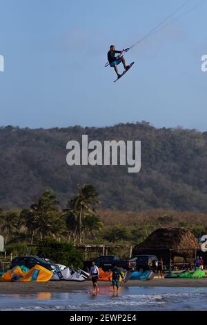 Man kiteboarder performing kitesurfing unhooked tricks, boy kitesurfer ...