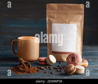 coffee beans, paper pack, macaroons and chocolate on wooden background ...
