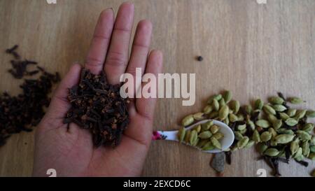 A man holding cardamom pods and cloves in his palm. Indian organic ...