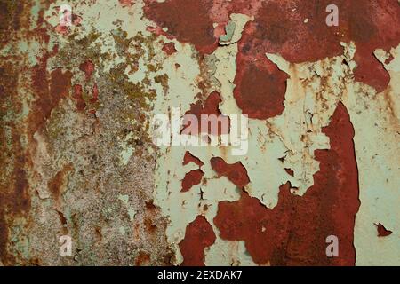 rusty metal sheet with peeling layers of paint of different colours - a ...