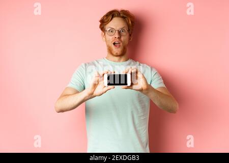 Amazed redhead man gasping and staring with awe at camera, showing ...