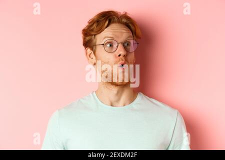 Face of intrigued young man with ginger hair and beard, raising ...