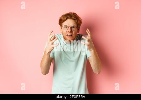 Angry redhead guy in glasses shouting, frowning and shaking hands with ...