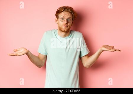 Image of clueless young man in sweater and santa hat, shrugging and ...