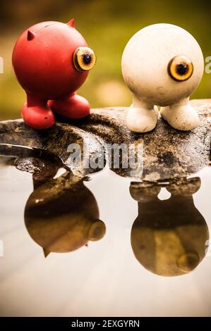 Two small red round toys with one eye on a book Stock Photo - Alamy
