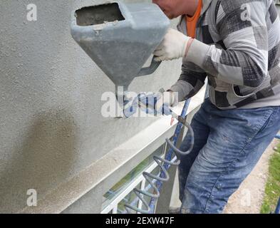 A man is applying stucco on the wall, plastering, coating the wall by ...