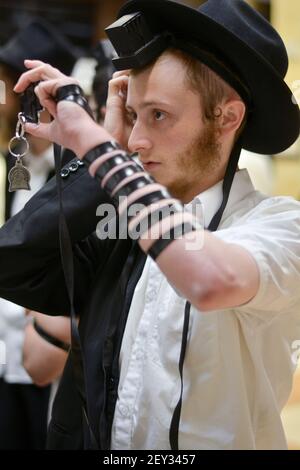 A jewish young man puts on his tefillin (phylacteries) in a Chabad ...