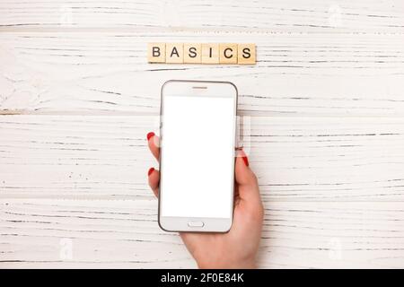 Basic income written on wood blocks with woman hand and smartphone on ...