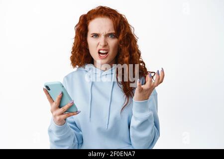 Young redhead woman angry and mad raising fist frustrated and furious ...