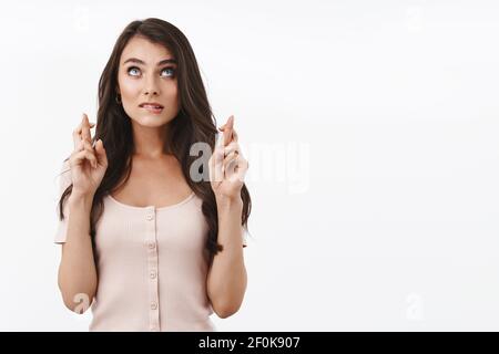 Hopeful cute brunette girl cross fingers good luck, making wish or ...
