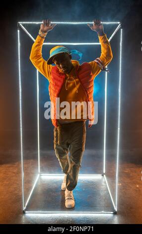 Young stylish rapper poses in illuminated cube. Hip-hop performer, rap ...