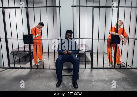 A strong black prison guard guards the cells with prisoners in the ...