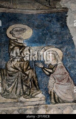 A tonsured monk looks up to heaven as he blesses a praying woman ...