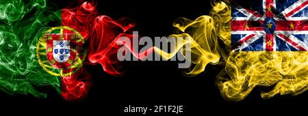 Niue and Portugal flag waving in the wind against white cloudy blue sky ...