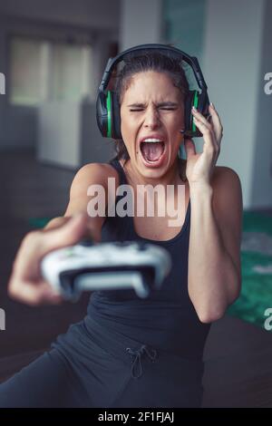 Young Caucasian angry gamer woman shouting while playing consol view ...