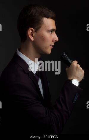 Man reporter holds microphone on a street promenade by a waterfront ...