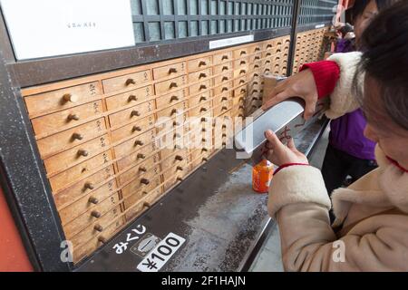 Woman drawing an Omikuji stick as part of Omikuji fortune telling at ...