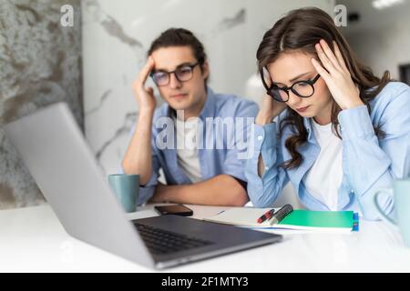 Sad couple with financial problems and troubles showing the calculator ...