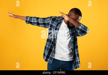 Man throwing dab, making internet meme pose on yellow background Stock ...