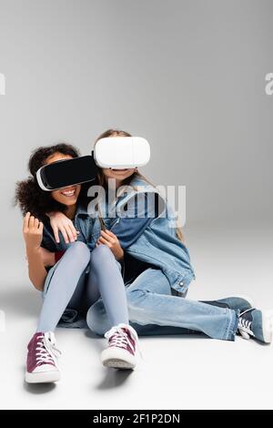 Frightened African American girl with VR glasses on eyes smiling leans ...