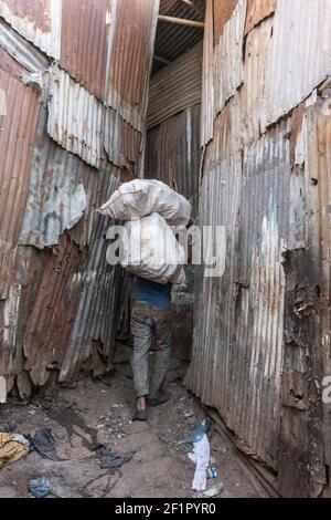 Ethiopia, Addis Ababa - Man carrying bags of merchandise walks through ...