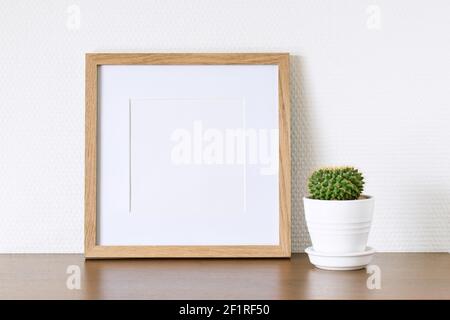 Table with blank photo frame and cactus near green wall in room Stock ...