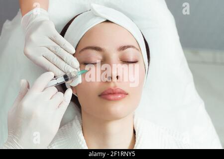 The doctor cosmetologist makes the Rejuvenating facial injections ...