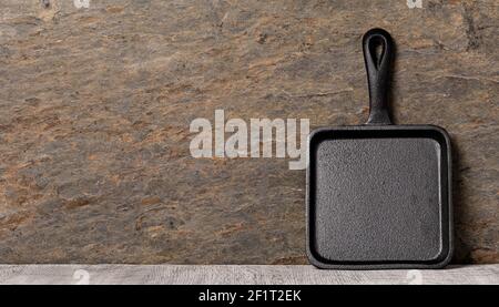 Brown iron empty pan with kitchen utensils on a dark concrete ...