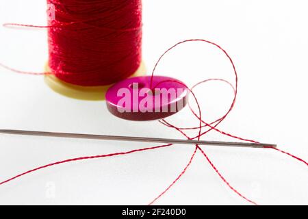 Button with two holes. Thin red thread Stock Photo - Alamy