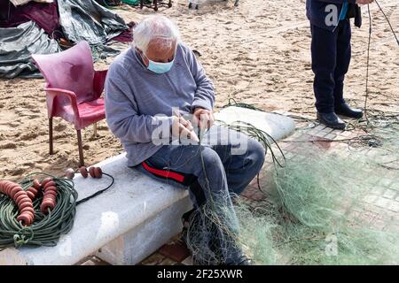 Huelva, Spain - February 27, 2021: A fishing net is being repaired by a ...
