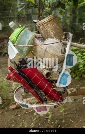 A vertical shot of random dirty pieces of plastic in a net hanging from ...