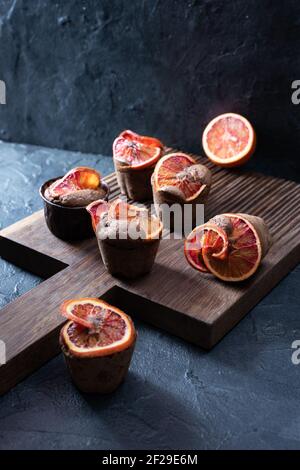 Blood oranges chocolate brownie muffins at brown oak cutboard on dark ...