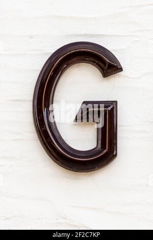 Dark brown glazed letter ü on a light wall Stock Photo - Alamy