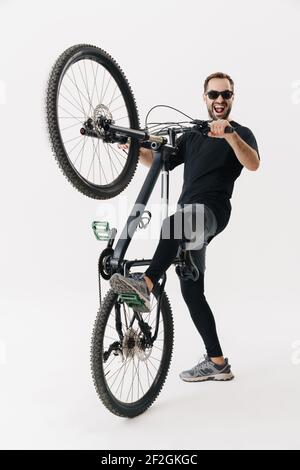 Excited young rider man smiling while posing with his bicycle isolated ...