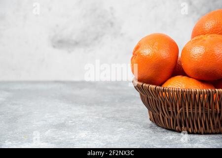 A wicker box full of juicy orange fruits on stone background Stock ...