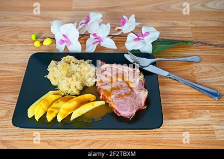 salted meat with sauerkraut and potato wedges arranged on black plate Stock Photo - Alamy