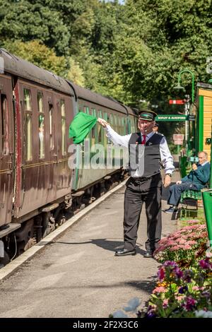 A train guard waves his green flag to the train driver beside a BR ...