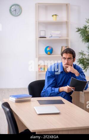Young teacher checking notes in the classroom Stock Photo - Alamy
