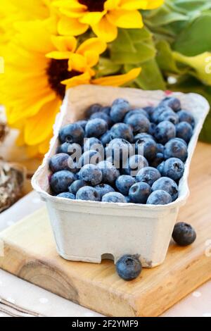 Paper box with blueberries and flowers in the background. Healthy food ...