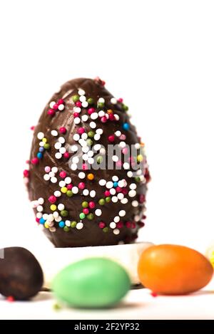 Chocolate Easter eggs with candies and sprinkles on yellow background ...